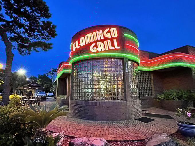 The iconic neon-lit exterior of Flamingo Grill stands as a beacon of culinary promise, its distinctive glass block windows and brick façade hinting at the retro elegance within.