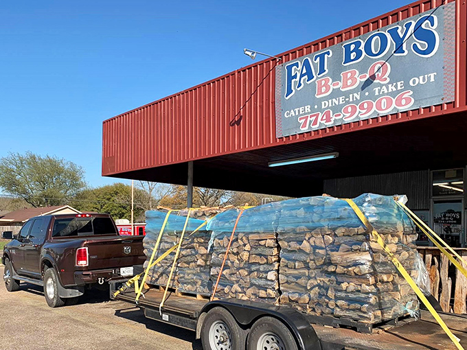 The unmistakable red exterior of Fat Boy's BBQ stands as a beacon of hope for hungry travelers. That trailer of wood isn't decoration—it's serious smoking business.