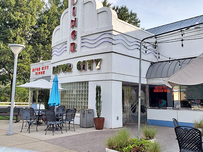 The sleek, retro-modern exterior of River City Diner beckons with its distinctive blue trim and inviting patio seating—a roadside oasis for hungry travelers.