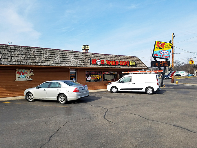 American flags flutter above Hog Wild's rustic exterior like patriotic smoke signals, beckoning hungry travelers with the promise of barbecue bliss beneath those cheerful red umbrellas.