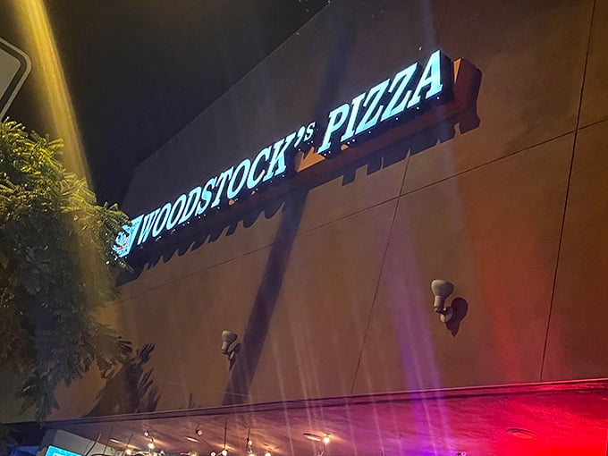 The neon glow of Woodstock's Pizza sign cuts through the night like a beacon for hungry travelers. Pizza paradise awaits.
