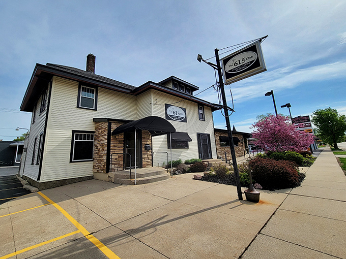 The cream-colored exterior with stone accents and black awnings whispers "classic Wisconsin supper club" without shouting. Culinary treasures await behind that unassuming façade.