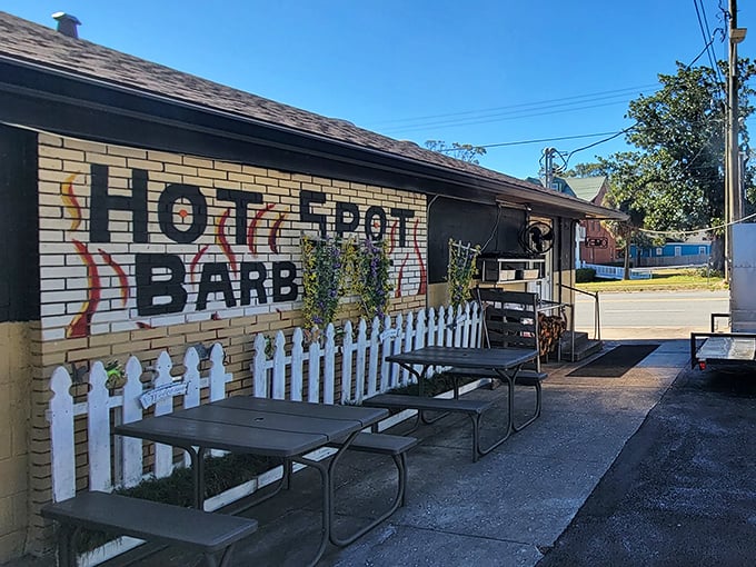 The unassuming yellow brick exterior of Hot Spot Barbecue is like a barbecue speakeasy – no fancy frills, just a white picket fence guarding smoky treasures within.