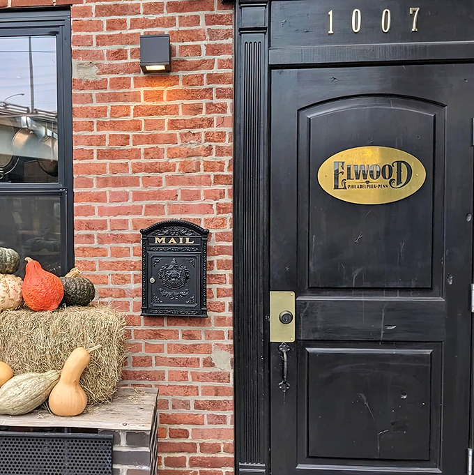 The unassuming entrance to culinary paradise – a black door with a golden Elwood plaque that promises treasures beyond the brick facade.