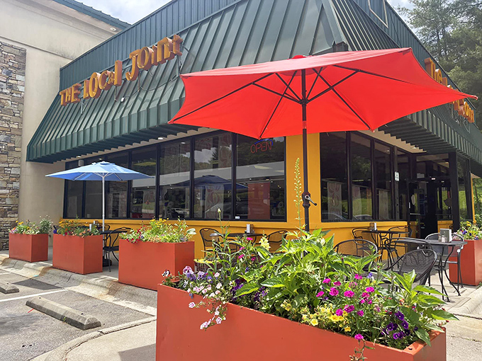 The cheerful yellow exterior with vibrant red planters says "happiness served here" before you even walk through the door.