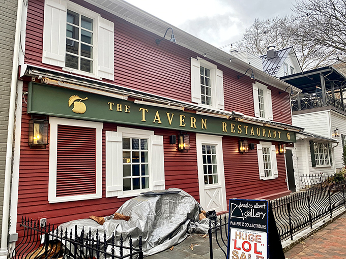 The iconic burgundy exterior of The Tavern stands as a beacon of culinary tradition in State College, complete with charming striped awnings and outdoor seating.