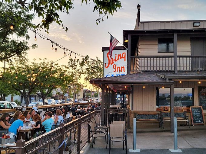 The Swing Inn's exterior beckons with its rustic charm and vibrant red umbrellas – like a Western saloon that decided to get serious about brunch.