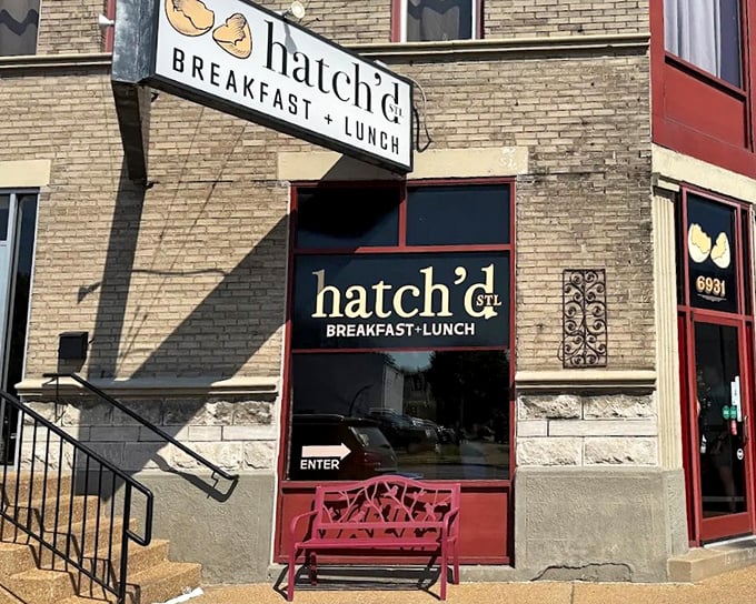The charming brick exterior of hatch'd STL beckons hungry St. Louis locals with its vintage signage and welcoming red bench—breakfast paradise found!