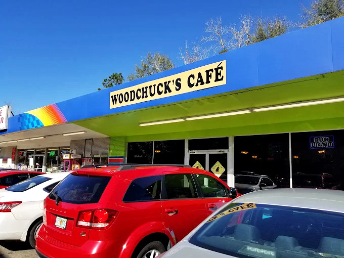 The vibrant blue exterior of Woodchuck's Cafe announces itself with colorful street art and a distinctive green awning—Tallahassee's breakfast rebellion in architectural form.
