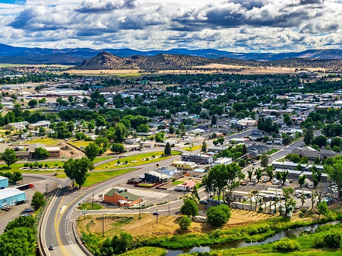 Prineville nestles in its high desert valley like a watercolor come to life, with the Crooked River curving gently alongside and dramatic rimrock buttes standing sentinel beyond.