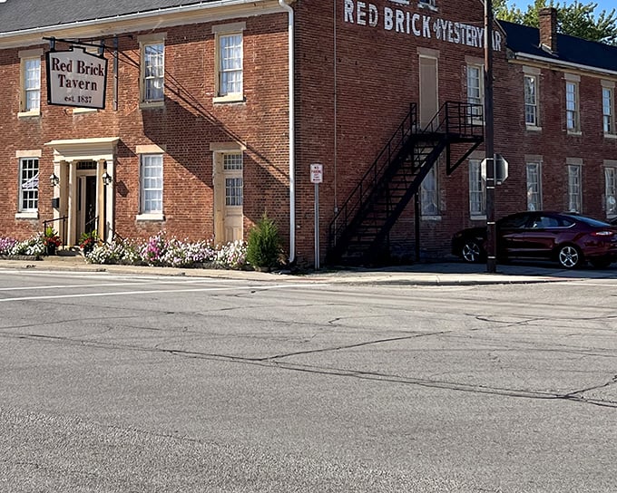The historic Red Brick Tavern stands proudly since 1837, its weathered facade a testament to nearly two centuries of welcoming hungry travelers along the National Road. 