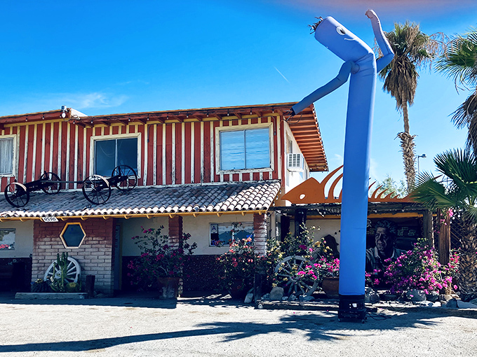The iconic blue tube man waves you in like an old friend, standing guard outside this desert oasis where adventure awaits.