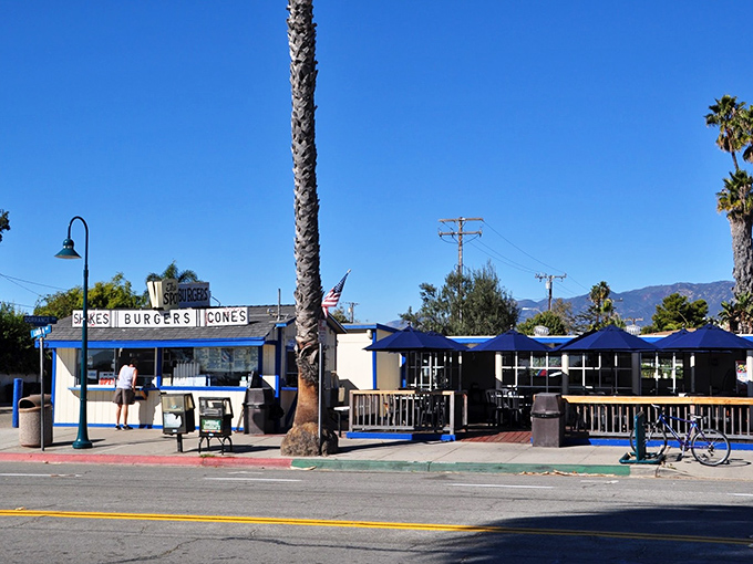 The quintessential California beach shack dream—palm trees, blue skies, and a sign promising the holy trinity: shakes, burgers, cones.
