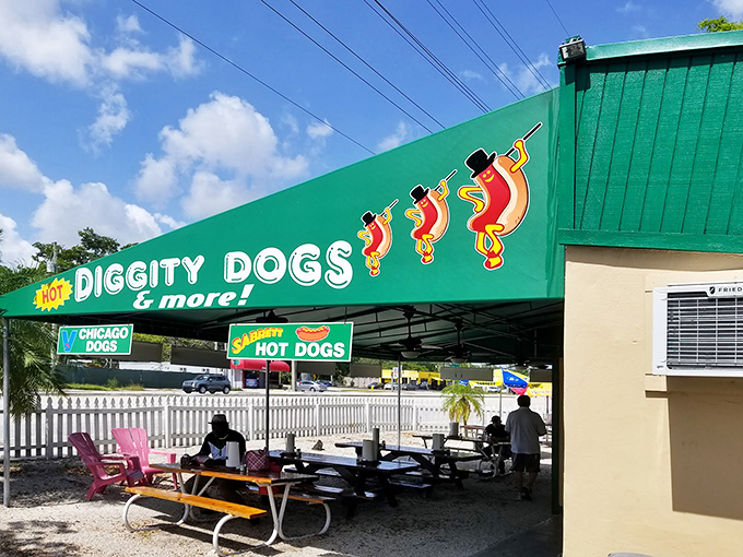 The iconic green awning of Hot Diggity Dogs beckons like a beacon of hope for the hungry. Simple picnic tables promise no pretense—just delicious satisfaction ahead.