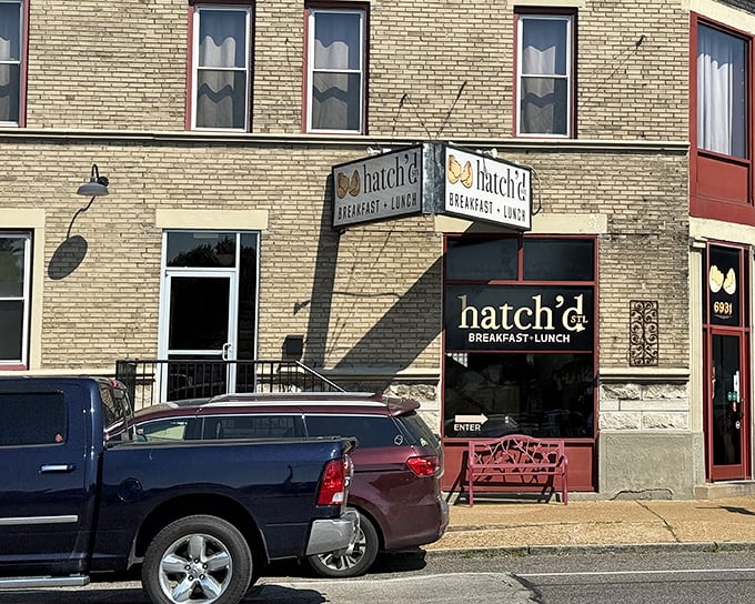 The iconic Hatch'd STL storefront beckons with its charming red bench and cracked egg logo—like a breakfast beacon in St. Louis brick.