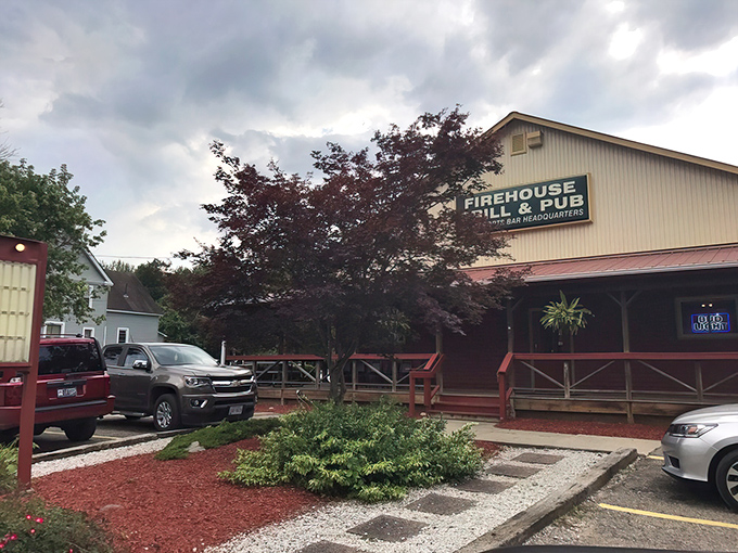 The distinctive red exterior of Rootstown Firehouse Grille & Pub welcomes visitors with its charming wraparound porch and cozy small-town appeal.