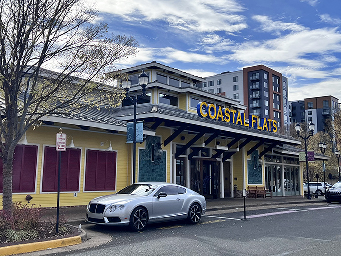 The sunshine-yellow exterior of Coastal Flats stands out like a cheerful beacon, promising seafood treasures within its nautical embrace.