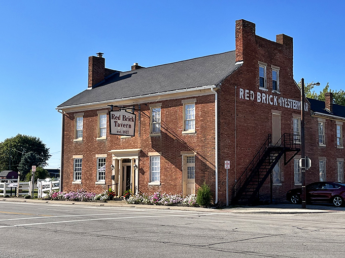 The historic Red Brick Tavern stands proudly along the National Road, its weathered façade a testament to nearly two centuries of American history and hospitality.