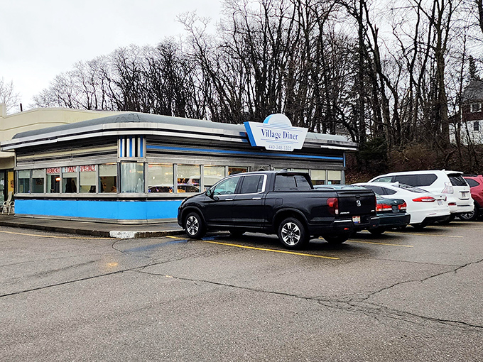 The classic blue-trimmed exterior of Village Diner stands like a time capsule of Americana, beckoning hungry travelers with its nostalgic charm.