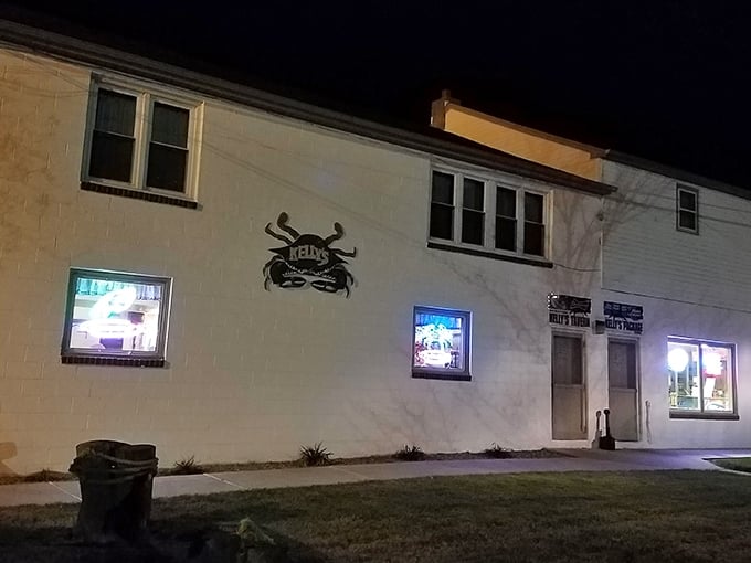 The unassuming white exterior of Kelly's Tavern, where that iconic crab sign promises more flavor than flash. Delaware seafood paradise found!
