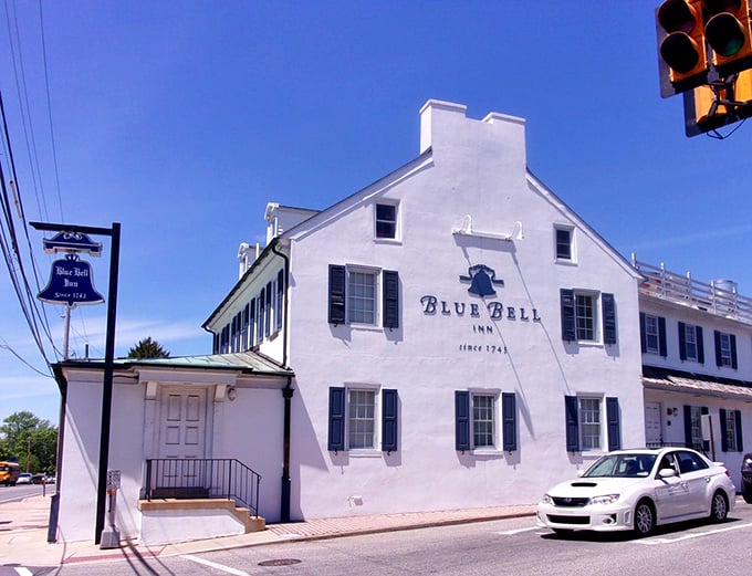 The historic Blue Bell Inn stands proudly in Pennsylvania sunshine, its whitewashed colonial charm beckoning hungry travelers like a culinary lighthouse.