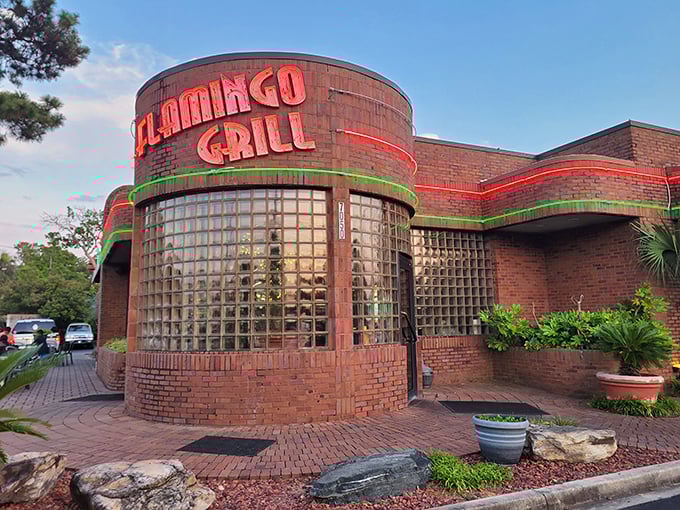 The iconic neon-lit exterior of Flamingo Grill stands as a beacon of culinary promise, its distinctive glass block windows and brick façade hinting at the retro elegance within.