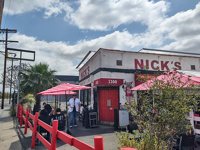 The iconic red-trimmed exterior of Nick's Café stands like a beacon of breakfast hope in downtown LA, complete with cheerful striped umbrellas and that unmistakable retro charm.