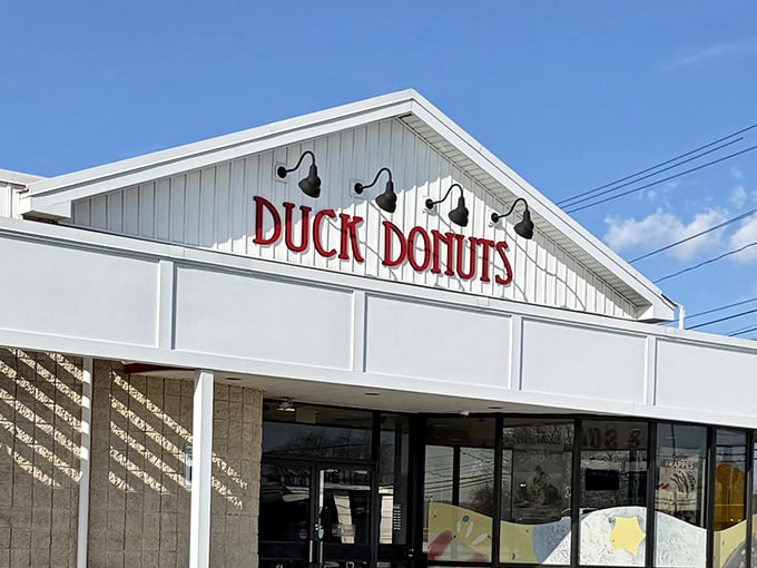 The white facade with bold red lettering promises donut nirvana. Those black lamps aren't just for show – they're illuminating the path to happiness.