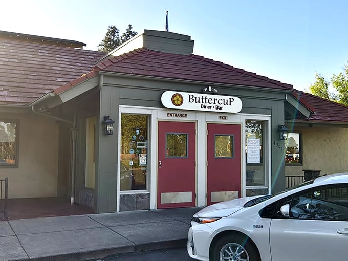 The charming exterior of Buttercup beckons with its burgundy doors and cozy stone accents—like a storybook cottage that happens to serve incredible eggs Benedict.