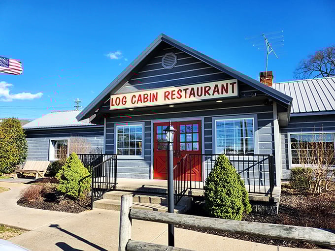 The blue exterior of Log Cabin Restaurant stands like a beacon of comfort food, complete with a welcoming red door that practically screams "get in here and eat something!"
