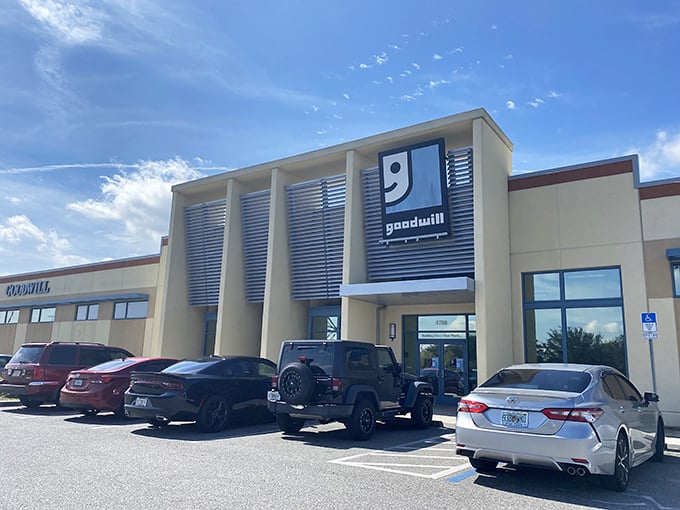 The modern exterior of Goodwill Goldenrod stands like a beacon of bargain hope under Florida's impossibly blue sky, promising air-conditioned treasure hunting inside.