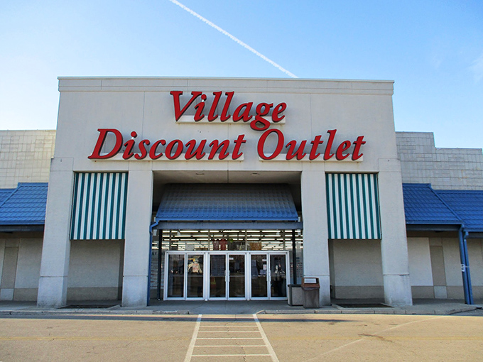 The iconic red lettering of Village Discount Outlet beckons bargain hunters like a retail lighthouse guiding ships to treasure-filled shores.