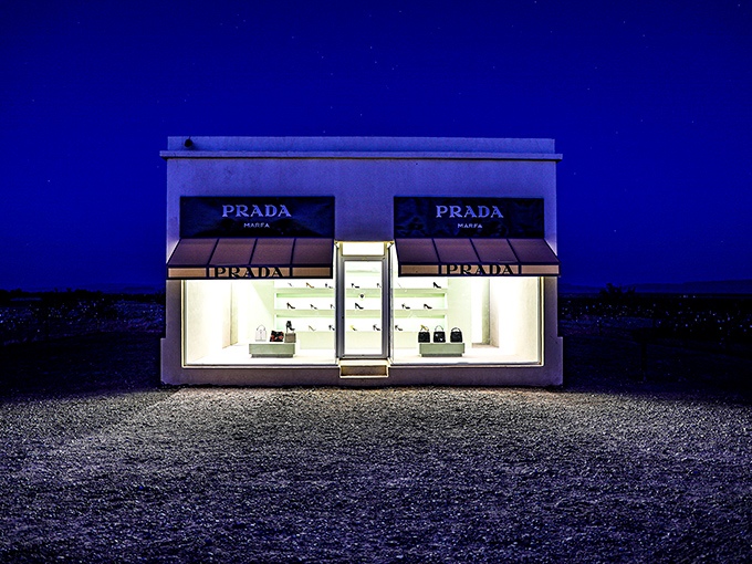 Prada after dark—where high fashion meets high desert under a canopy of stars. The illuminated storefront creates an otherworldly glow against the inky Texas night.