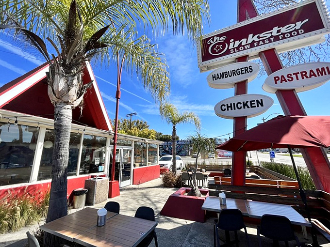 The iconic red A-frame of The Oinkster beckons like a delicious mirage, promising flavor salvation under the California sun. Fast food architecture meets slow food philosophy.