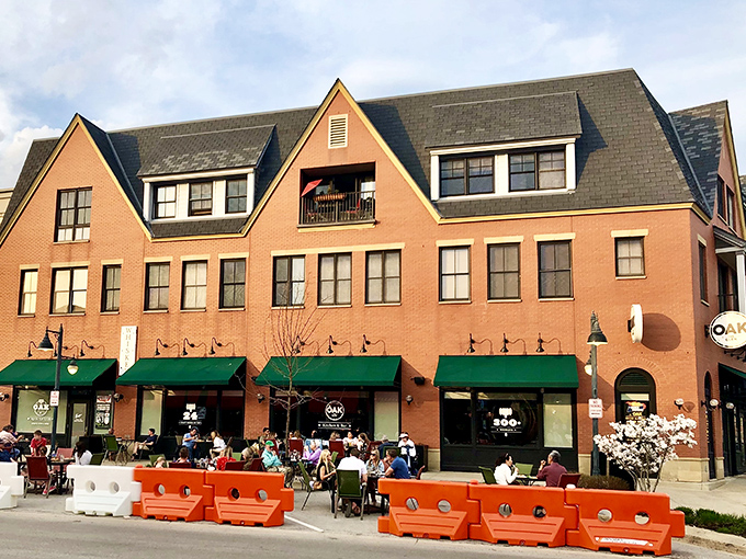 The welcoming brick facade of Oak at The Glen stands proudly in Glenview, where those orange barriers aren't keeping people out—they're creating the perfect outdoor dining sanctuary.
