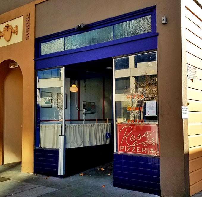 The unassuming blue-trimmed storefront of Rose Pizzeria might not scream for attention, but trust me—pizza paradise awaits behind that modest façade.