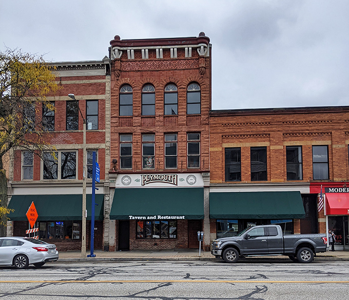The brick façade of Plymouth Tavern stands proudly on Erie's State Street, a three-story testament to timeless hospitality that beckons hungry travelers inside.