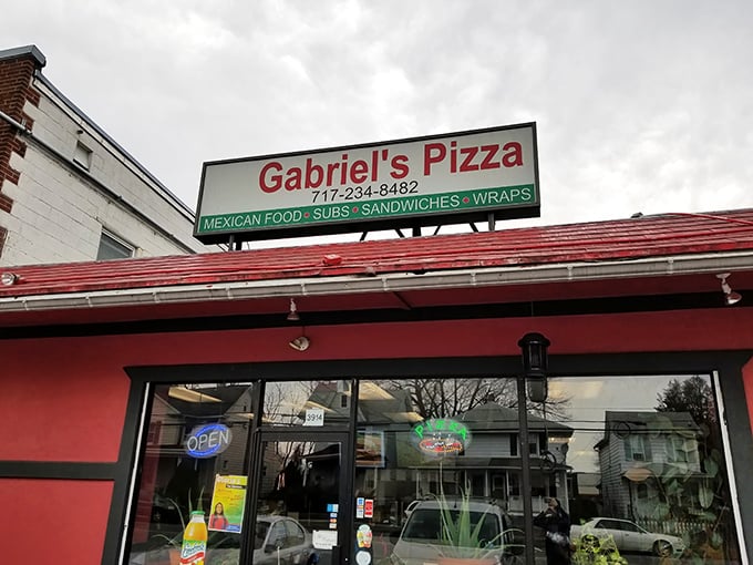 The bright red exterior of Gabriel's Pizza stands out like a beacon of hope for the hungry traveler. Simple signage promises multiple culinary adventures under one roof.