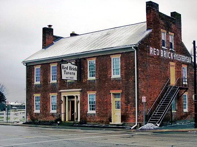 The historic Red Brick Tavern stands proudly along the National Road, its weathered façade a testament to nearly two centuries of American history and hospitality.