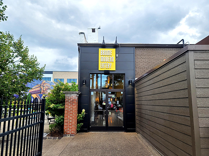 The sleek exterior of Brome Modern Eatery beckons with its bold yellow signage against dark walls—like a culinary lighthouse guiding hungry Michiganders home.