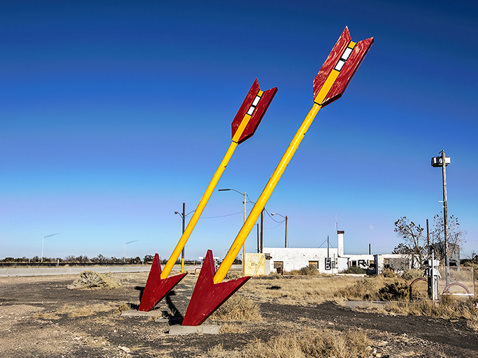 The iconic arrow pierces the Arizona sky like a relic from a forgotten road trip era, standing tall against the endless desert horizon.