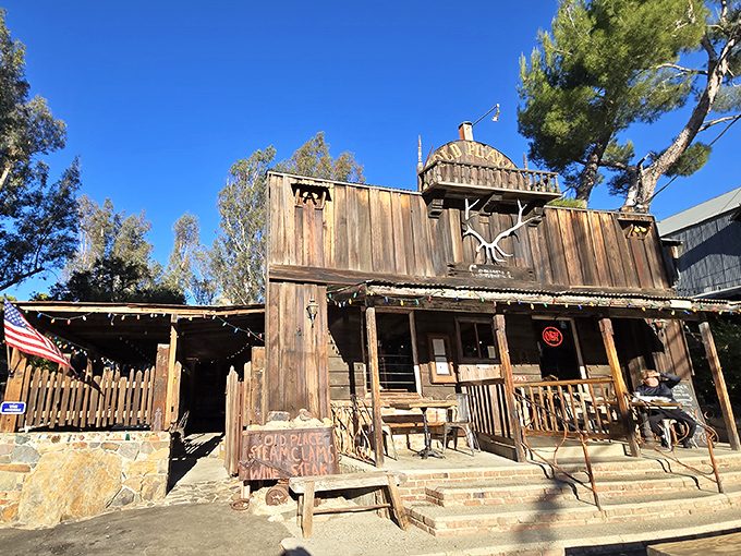The Old West meets modern California at The Old Place's rugged exterior. Motorcycles parked outside this weathered wooden structure hint at the diverse crowd this legendary steakhouse attracts.