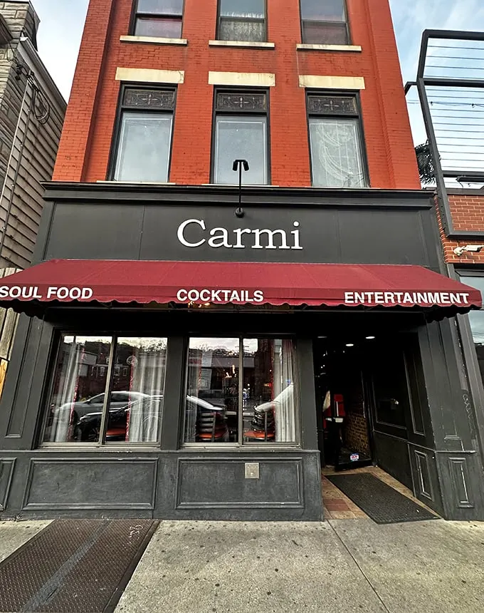 The iconic red awning of Carmi Soul Food beckons hungry travelers like a Southern lighthouse guiding ships to comfort food harbor.