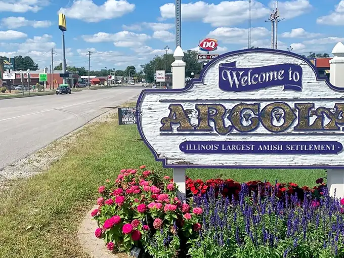 The welcome sign says it all – Arcola proudly embraces its Amish heritage while McDonald's and DQ stand nearby, a perfect metaphor for this charmingly contradictory town.