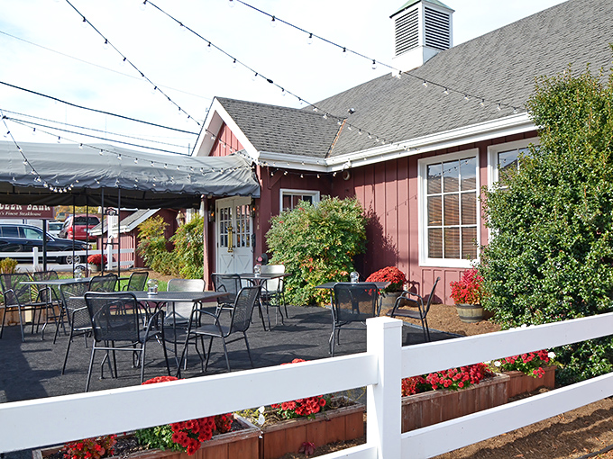 The barn-red exterior with white trim isn't just charming—it's a promise of the comfort food paradise waiting inside. String lights add a touch of magic to outdoor dining.