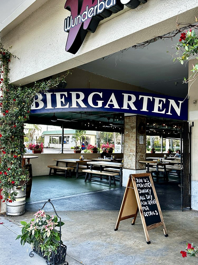 The inviting entrance to Wunderbar beckons with its vibrant blue "BIERGARTEN" sign and climbing vines—Bavaria's warm embrace in sunny Florida.