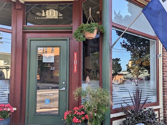 The charming exterior of Kitchen 101 beckons with its green door and vibrant flowers, like a culinary oasis on Chambersburg Street.