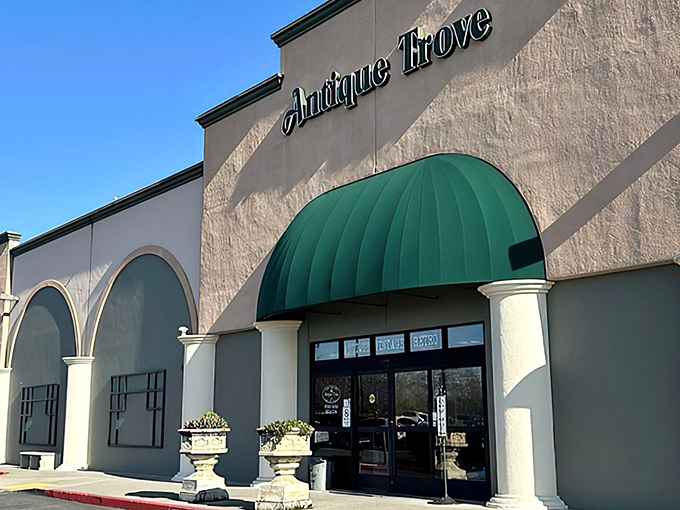 The stately facade of Antique Trove beckons with its elegant columns and distinctive green awning—architectural foreplay for the treasure hunt that awaits inside.