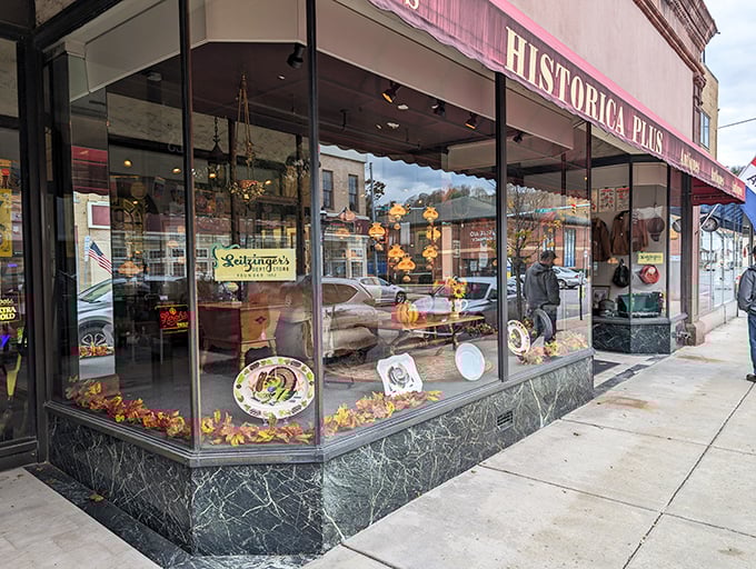 The storefront beckons with its classic display window, showcasing treasures arranged like a museum exhibit. Autumn leaves add seasonal charm to this vintage hunter's paradise.
