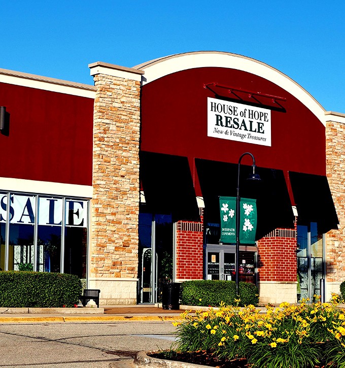 The welcoming facade of House of Hope Resale stands out with its distinctive red awning and stone accents—retail therapy with a conscience awaits inside.